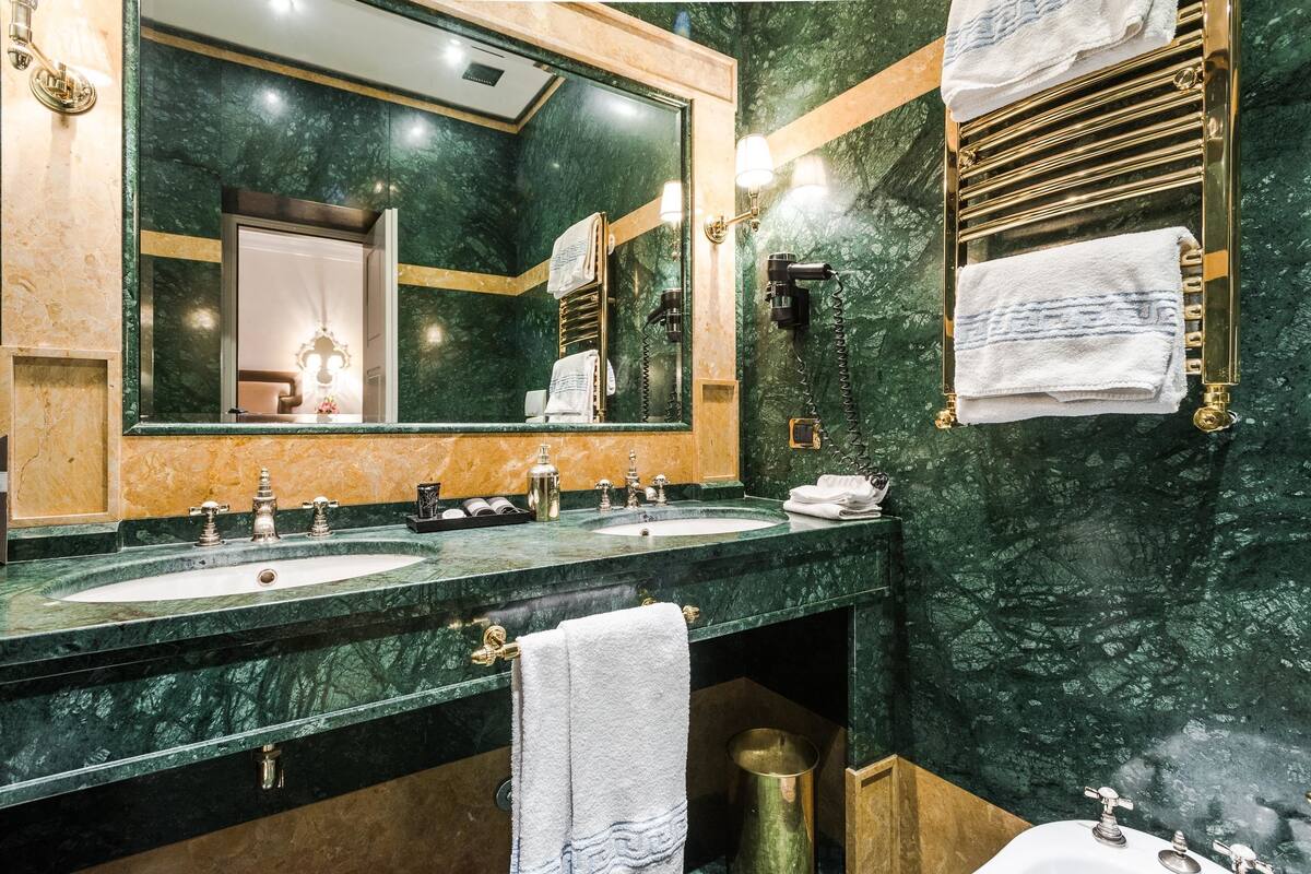 Casa de banho com duas pias, um espelho grande e porta-toalhas.