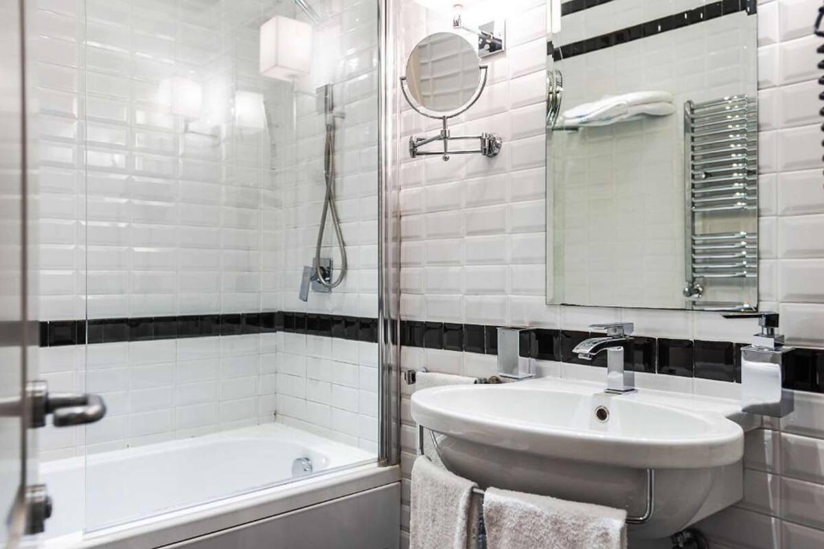 Casa de banho moderna com cabine de duche em vidro, lavatório branco e espelho grande.