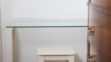 Um banquinho branco pequeno ao lado de uma prateleira de vidro.