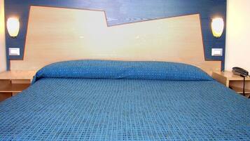 Quarto de hotel com uma cama grande, cabeceira de madeira, duas mesas de cabeceira e um telefone em uma delas.