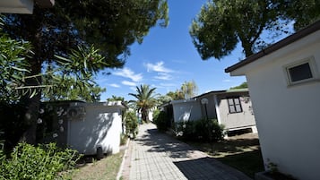 Uma trilha que leva a uma fileira de pequenas casas de campo brancas, sob um céu azul límpido.