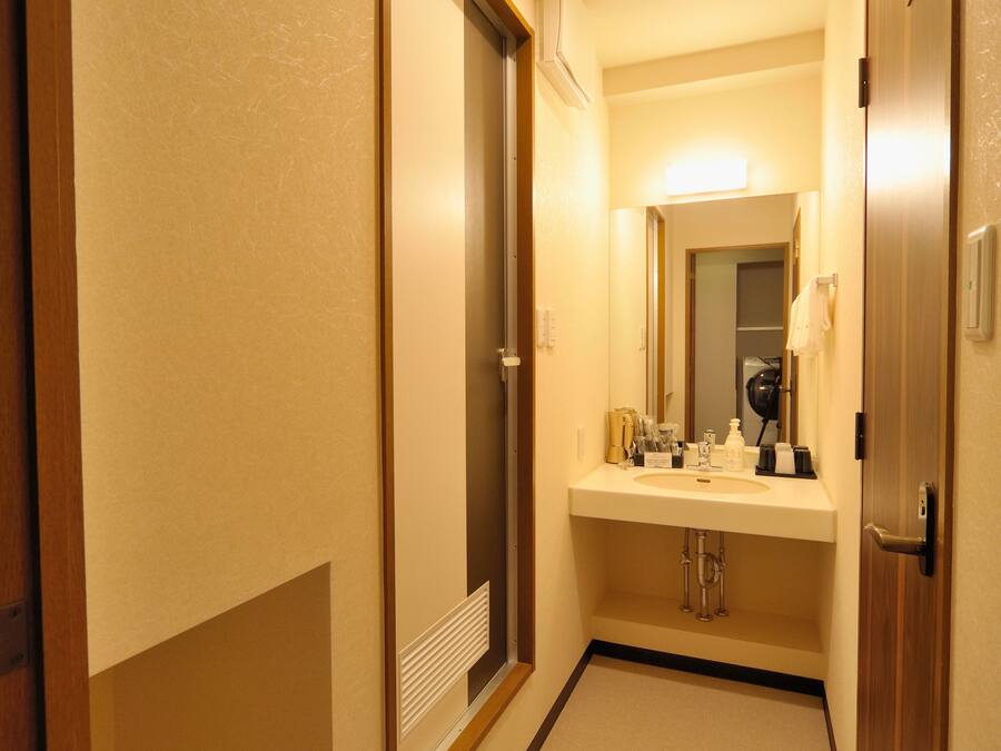 Corredor de hotel com banheiro, incluindo pia, espelho e porta-toalhas.