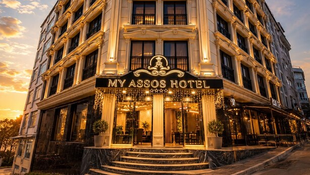 Hotel de vários andares com entrada imponente, placa visível e escadaria que leva à entrada.