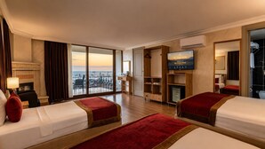Quarto de hotel com duas camas, televisão, lareira e varanda com vista.