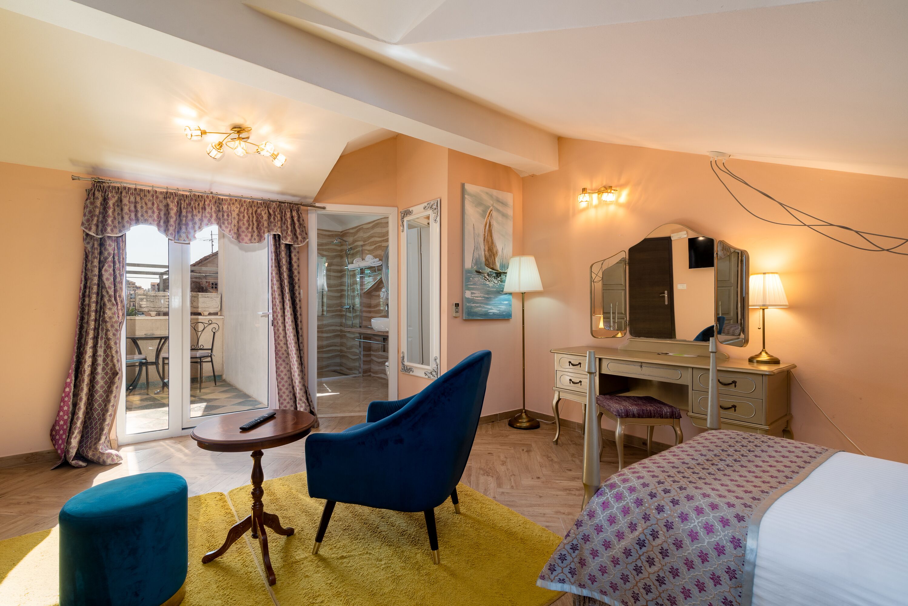 Quarto de hotel com uma cama, uma escrivaninha com cadeira, uma penteadeira com espelho e vista para o exterior.