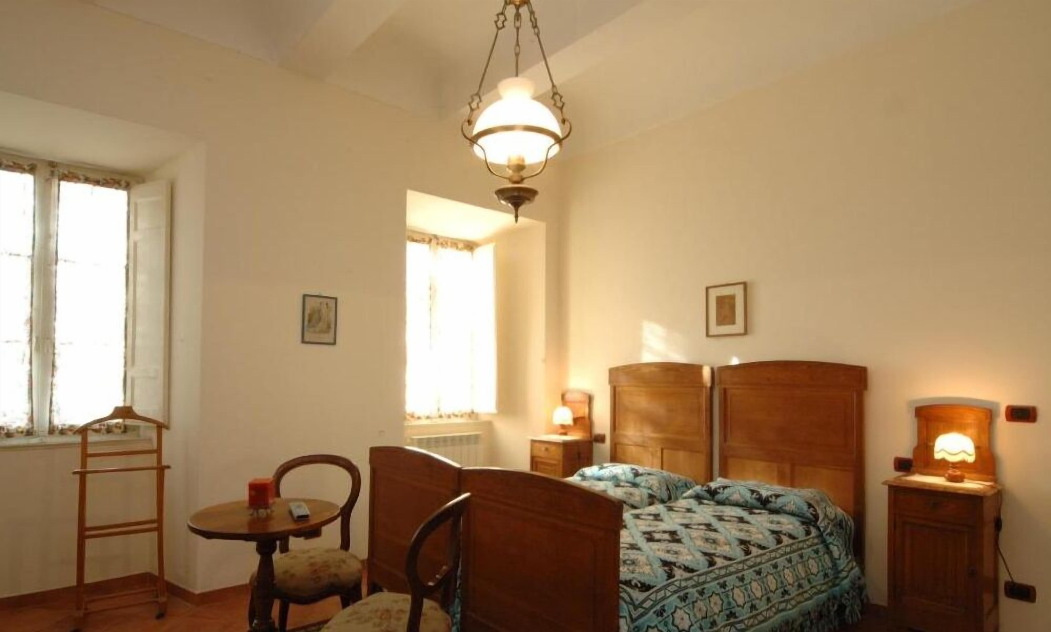 Quarto com cama, escrivaninha, cadeira, escada e luminária pendente.