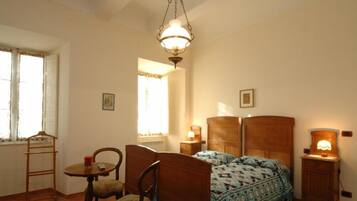 Quarto com cama, escrivaninha, cadeira, escada e luminária pendente.