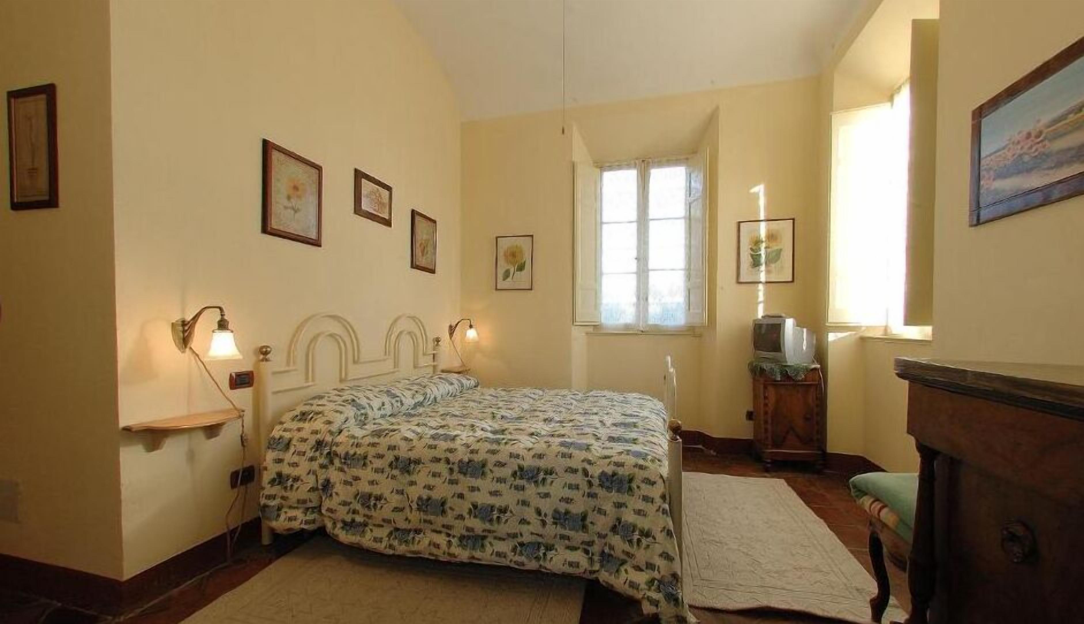 Quarto com cama, janela, escrivaninha e televisão.