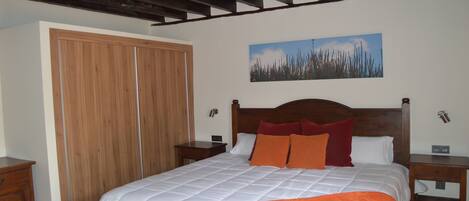 Quarto com cama de madeira, um guarda-roupa grande e uma pintura na parede.