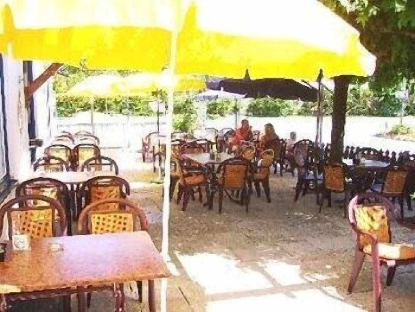 Área externa com mesas e cadeiras sob guarda-sóis amarelos.
