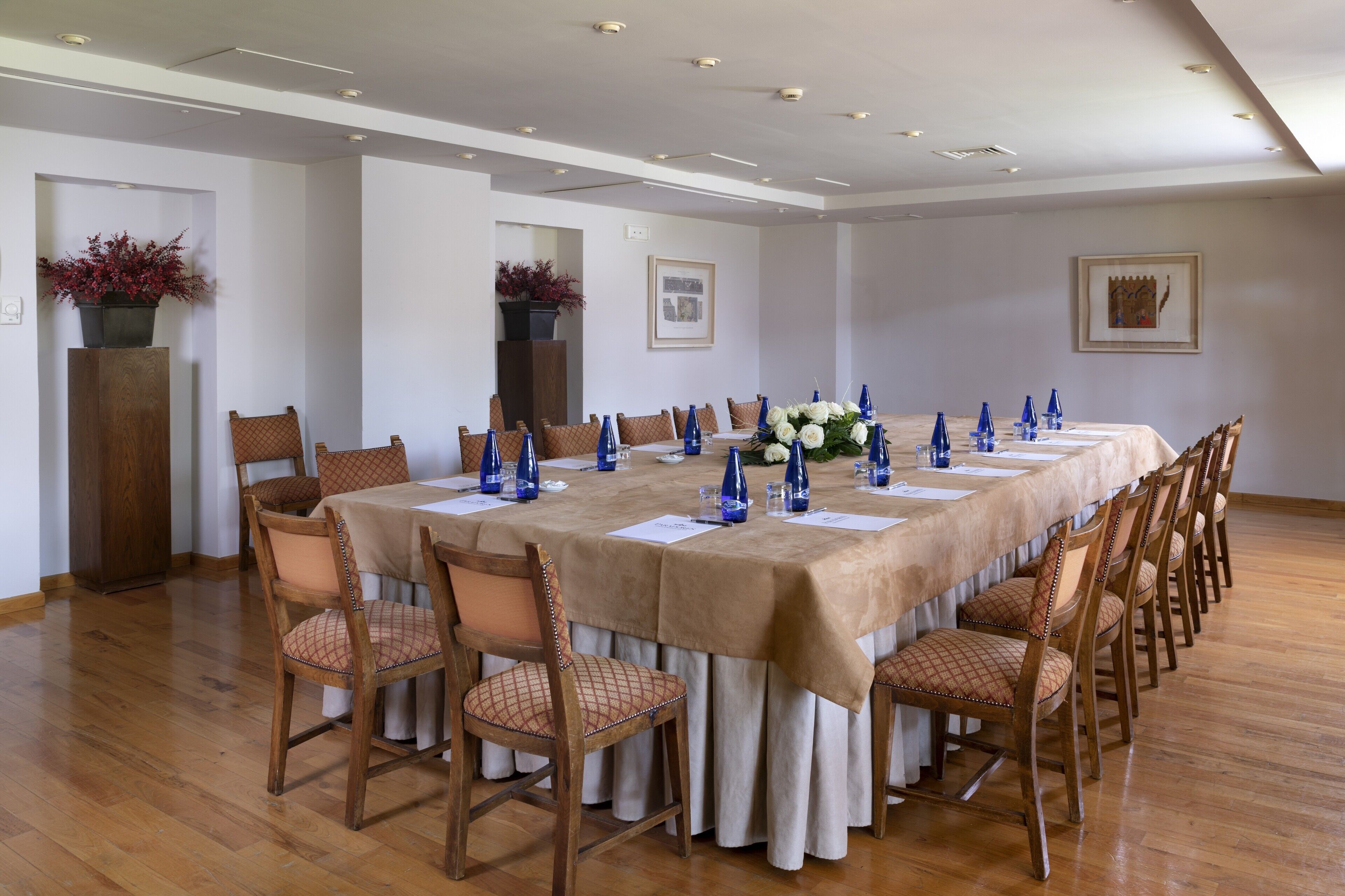 Uma sala de conferência com uma mesa comprida, cadeiras e garrafas de água azuis.