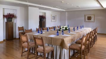 Uma sala de conferência com uma mesa comprida, cadeiras e garrafas de água azuis.
