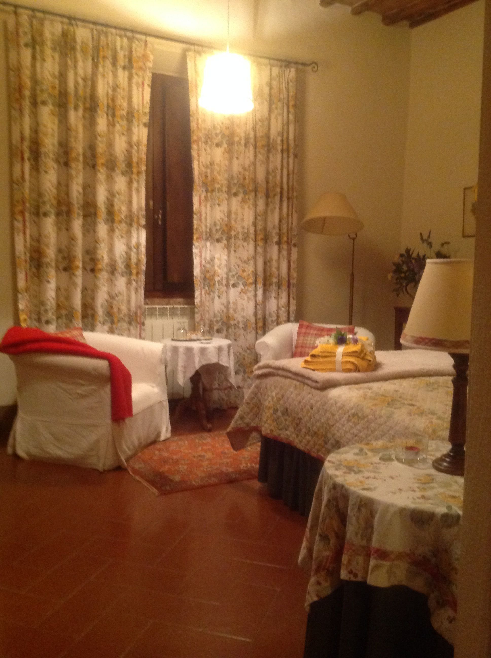 Um quarto acolhedor com uma cama, uma cadeira, uma mesinha e um abajur.