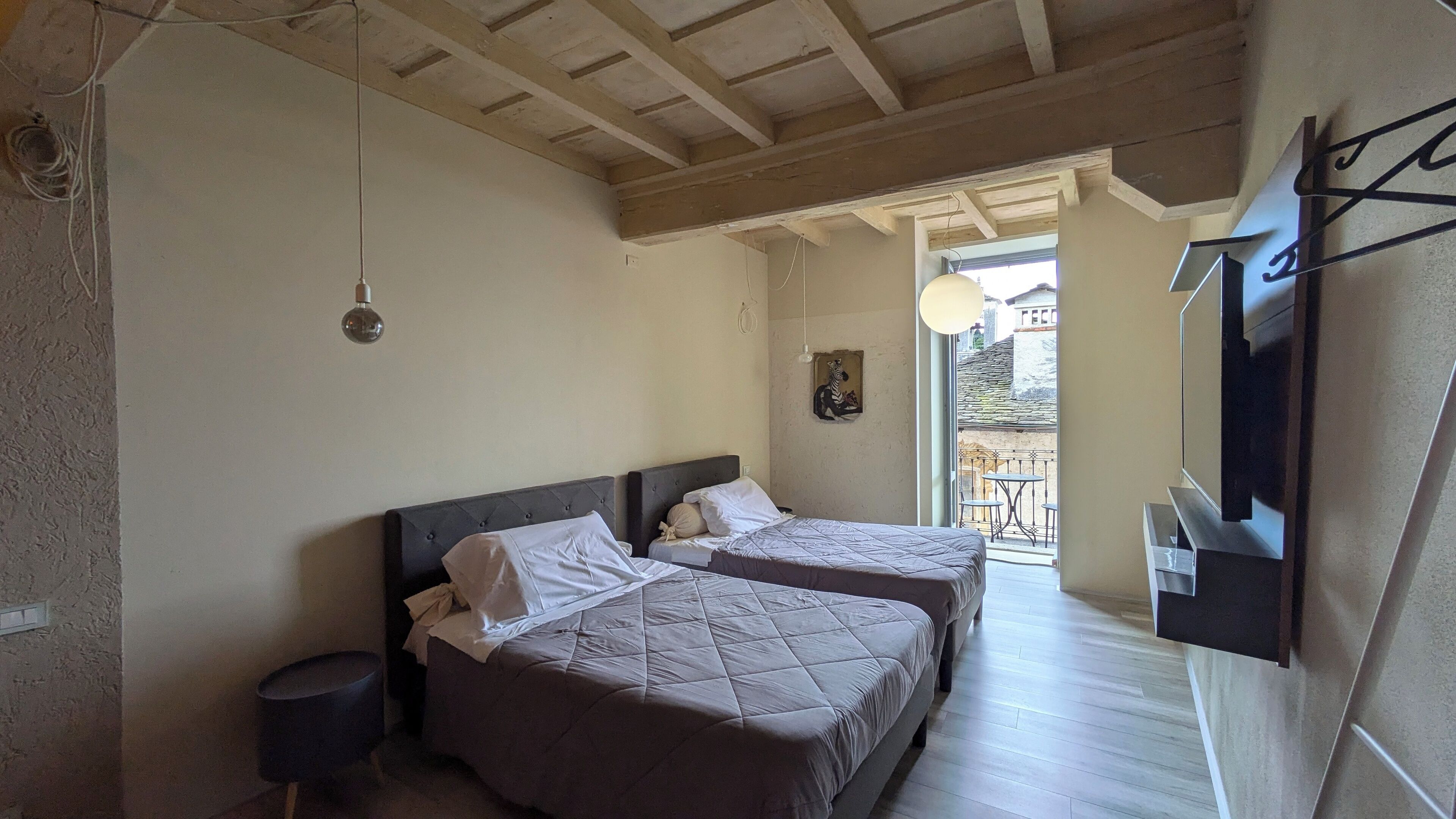 Quarto com duas camas, televisão e varanda com área de estar.