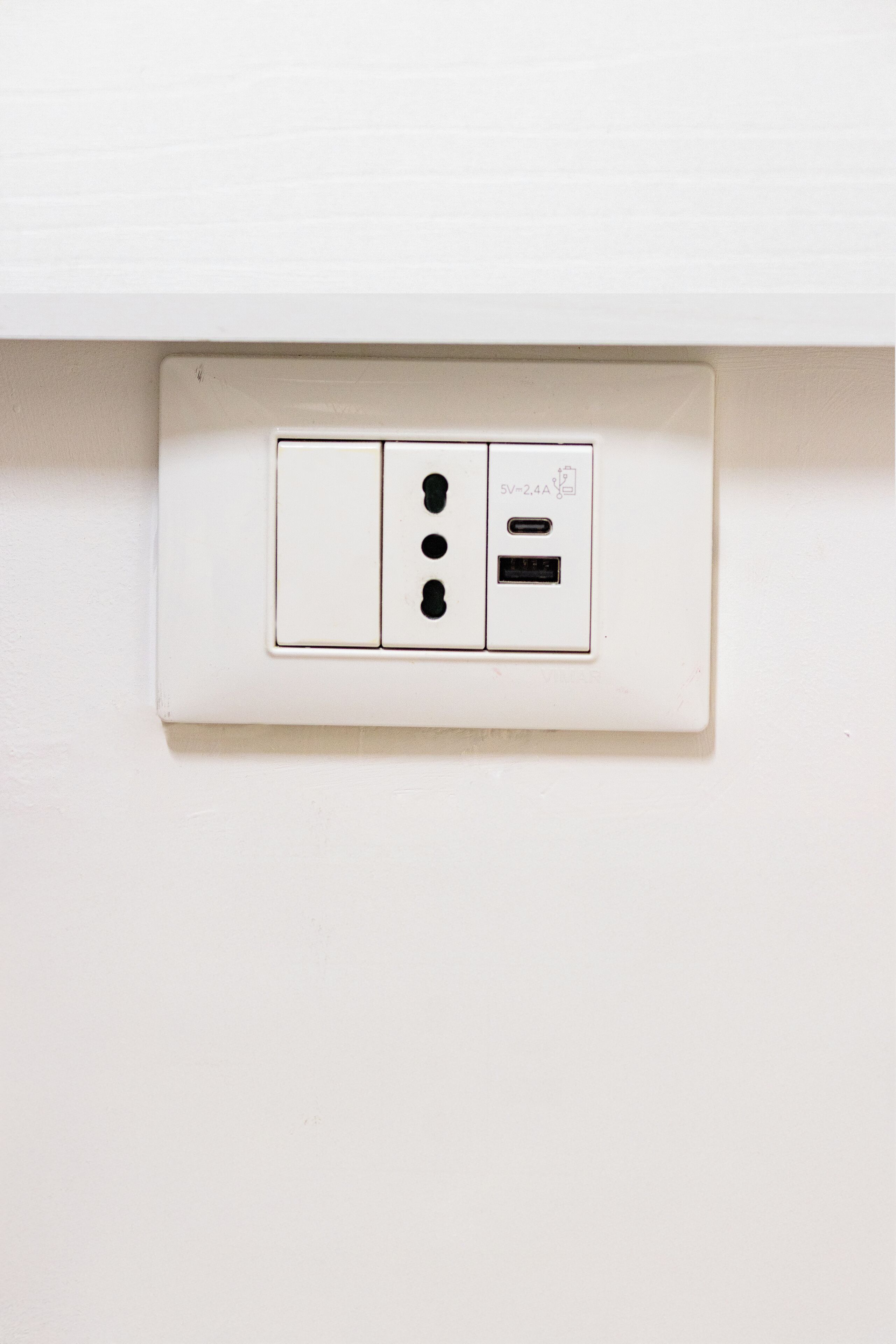 Uma tomada branca com três interruptores pretos e duas portas USB.