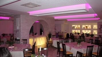 Um restaurante com várias mesas, cadeiras e um balcão de bar.