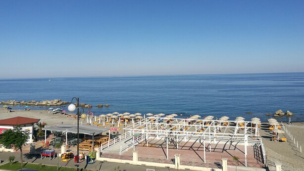 Um resort à beira-mar com área de piscina, guarda-sóis e vista para o oceano.