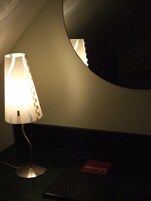 Luminária com cúpula branca e superfície refletora na parede.