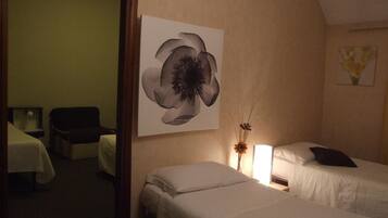 Quarto de hotel com duas camas, um espelho, um quadro e um vaso com flores secas.