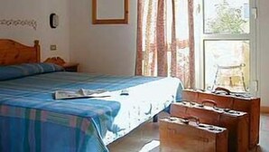 Quarto com cama, janela com cortinas, espelho e cabeceira de madeira.