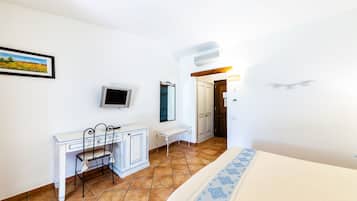 Um quarto com cama, escrivaninha com cadeira, televisão e guarda-roupa.