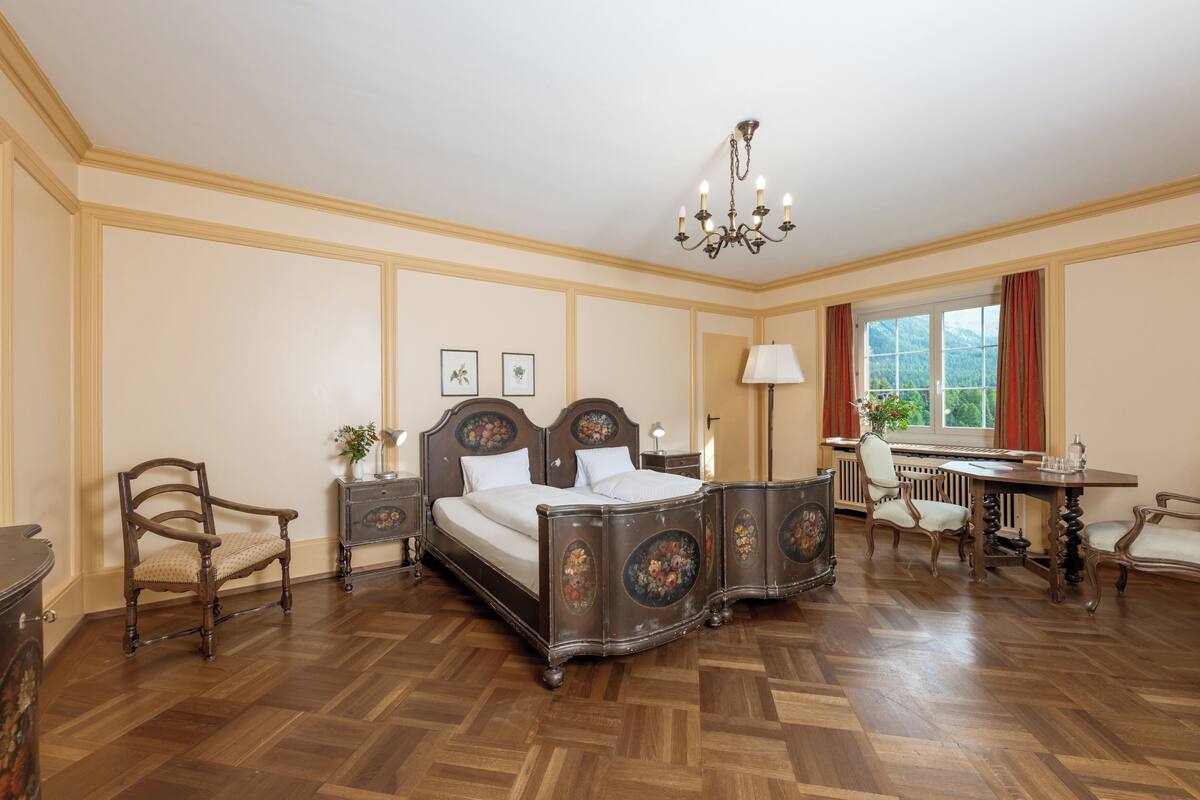 Um quarto clássico com uma cama de dossel, uma escrivaninha de madeira e uma cadeira.