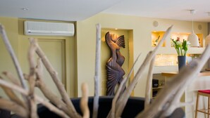 Interior moderno com uma escultura de madeira, área de bar com copos e ar condicionado instalado no teto.