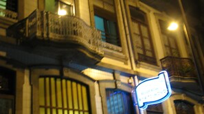 Fachada de edifício com uma varanda grande e elaborada, e um letreiro de neon.