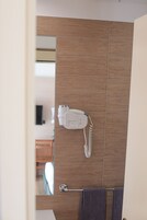 Um banheiro com azulejos de madeira, porta-toalhas, espelho e secador de cabelo na parede.