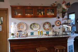 Cozinha com armário de madeira, bancada de mármore e diversos utensílios.