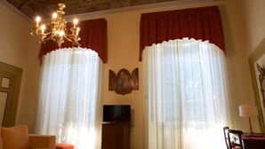 Um quarto com um candelabro, uma televisão e um armário de madeira.