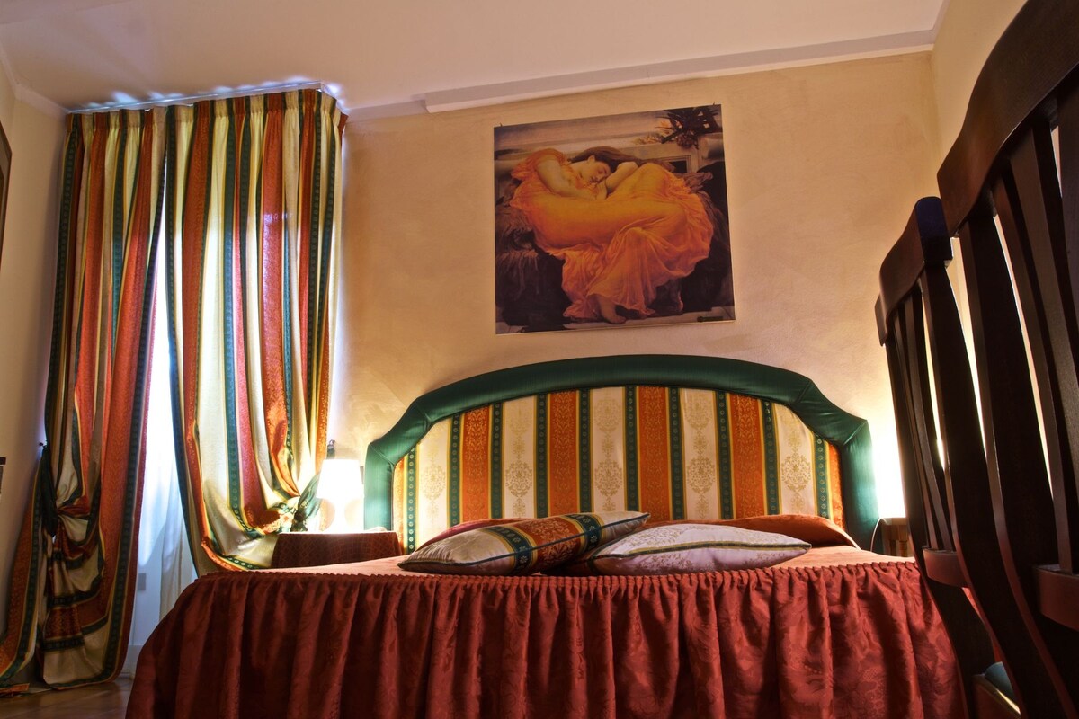 Quarto com cama, cabeceira, pintura na parede e cortinas.