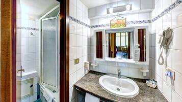 Casa de banho com lavatório, espelho e secador de cabelo fixado na parede.