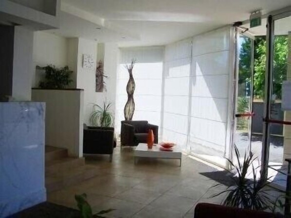 Uma sala espaçosa com uma grande porta de vidro deslizante que dá para uma varanda, um sofá, uma mesa de centro e um vaso decorativo.