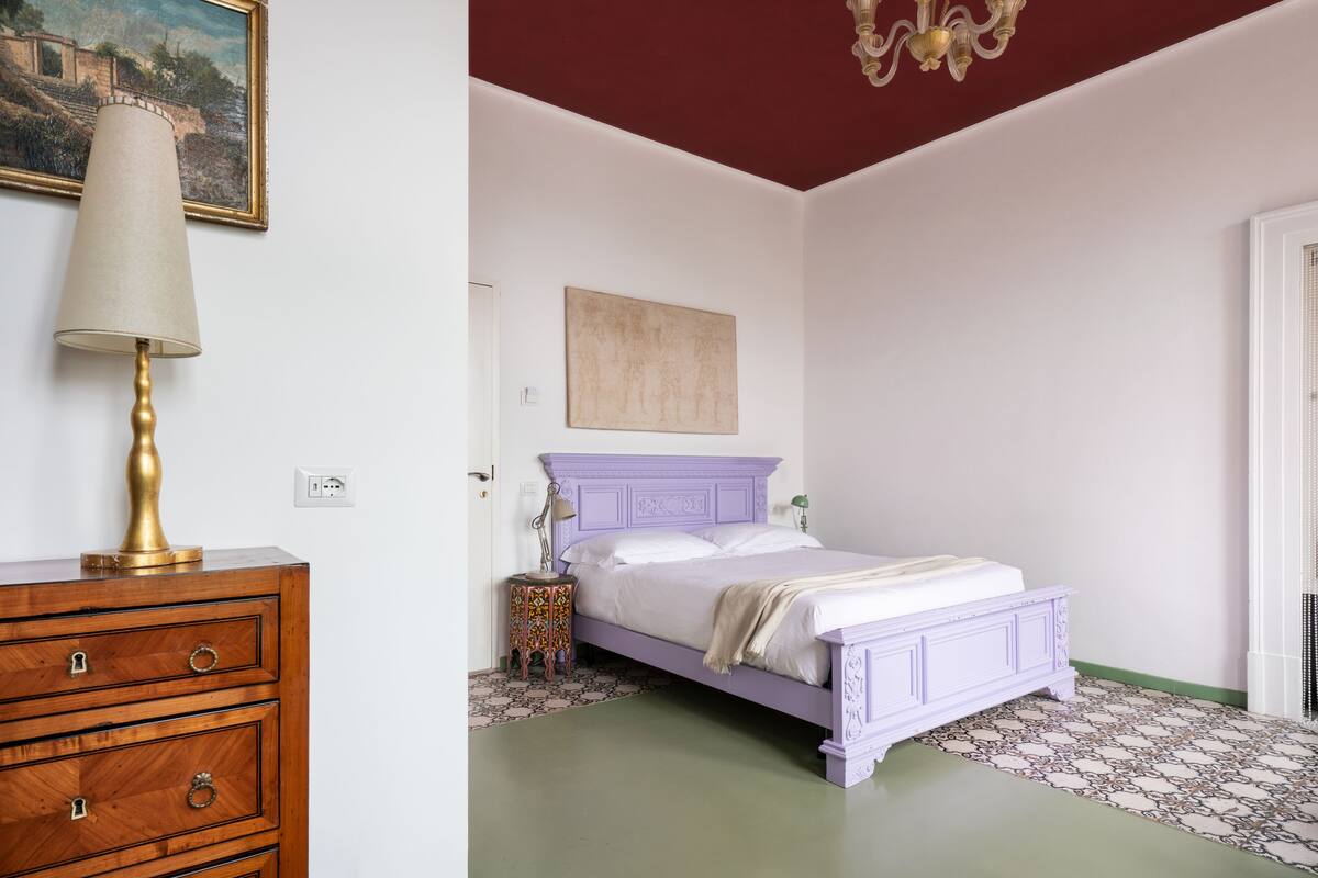 Quarto com cama, penteadeira, luminária e obra de arte na parede.