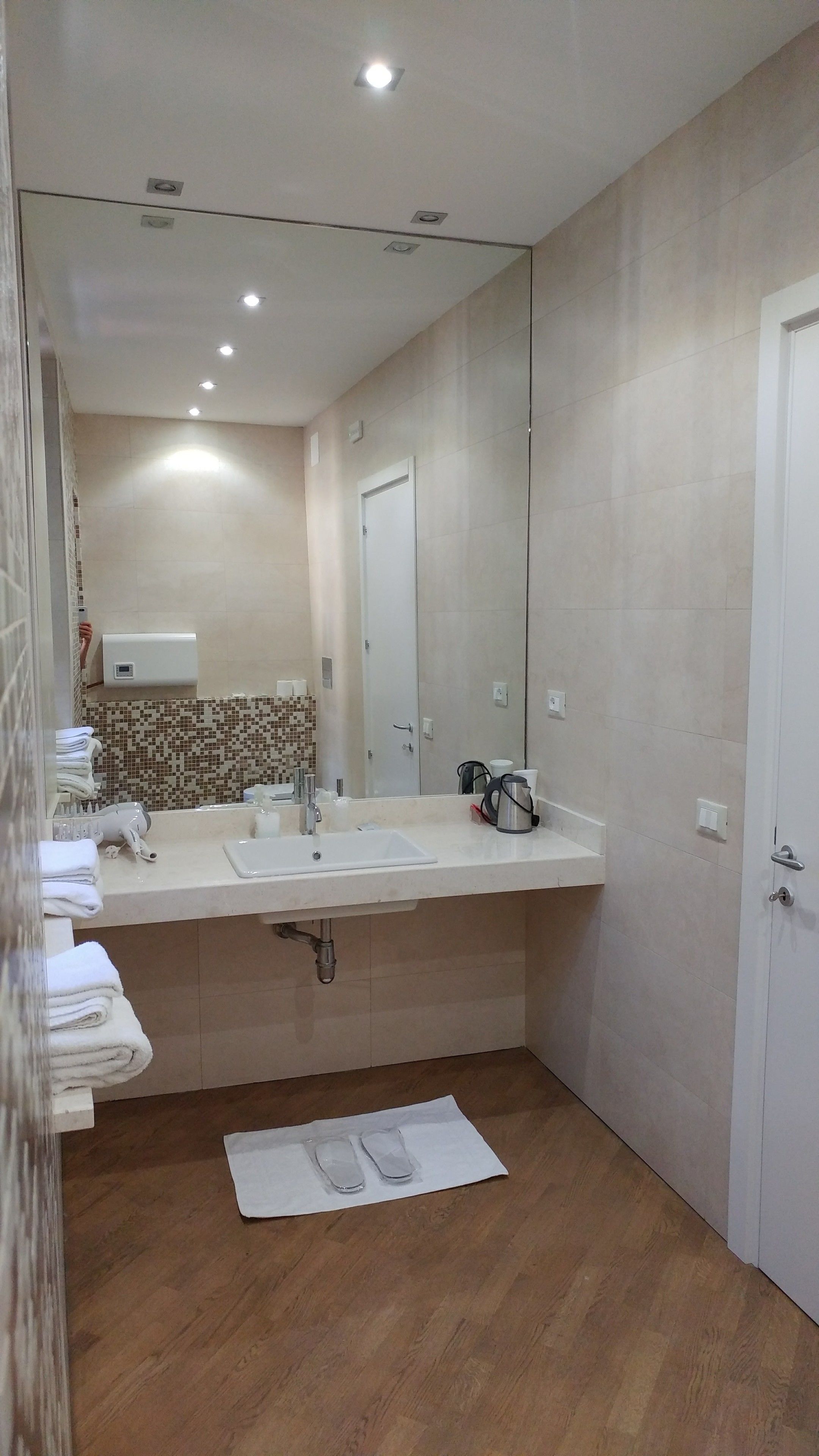 Uma casa de banho moderna com um espelho grande, lavatório e porta-toalhas.