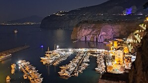 Uma marina à noite com barcos atracados, um cais e edifícios iluminados.