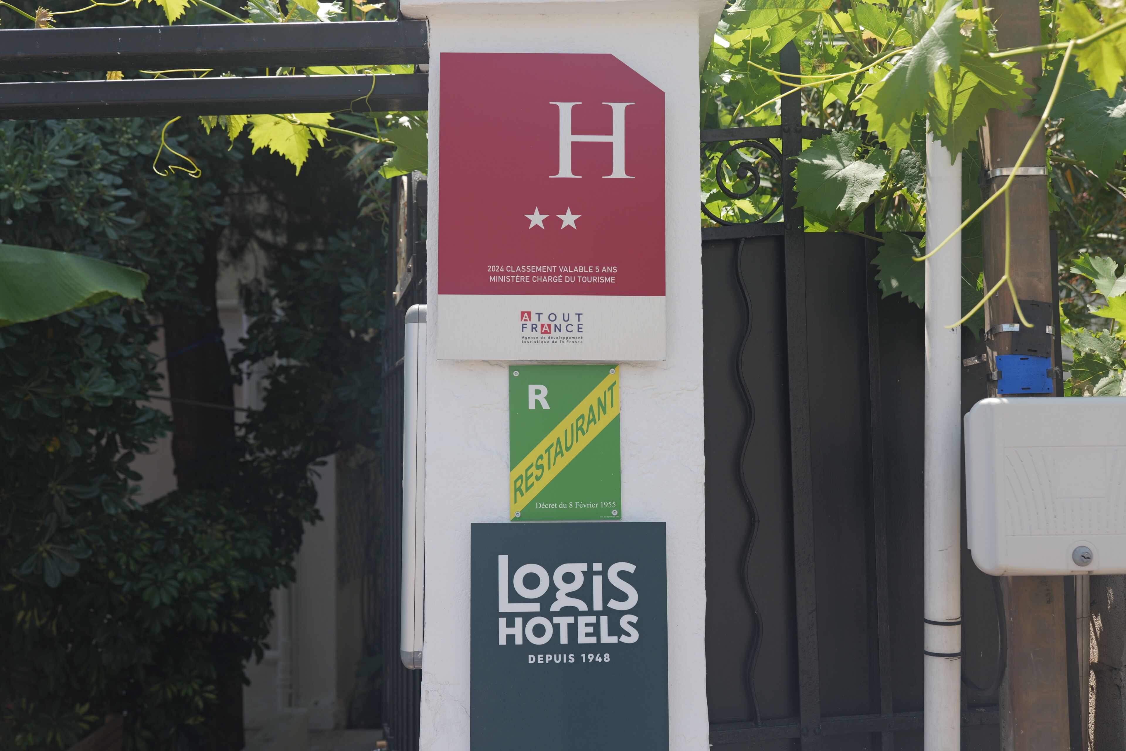 Uma placa com a letra 'H' e o logotipo da 'Logis Hotels', fundada em 1948.