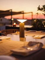 Uma vela sobre uma mesa com um pôr do sol ao fundo.