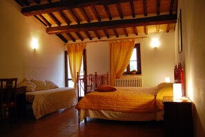 Quarto com duas camas, teto de madeira, radiador e janela com cortinas.