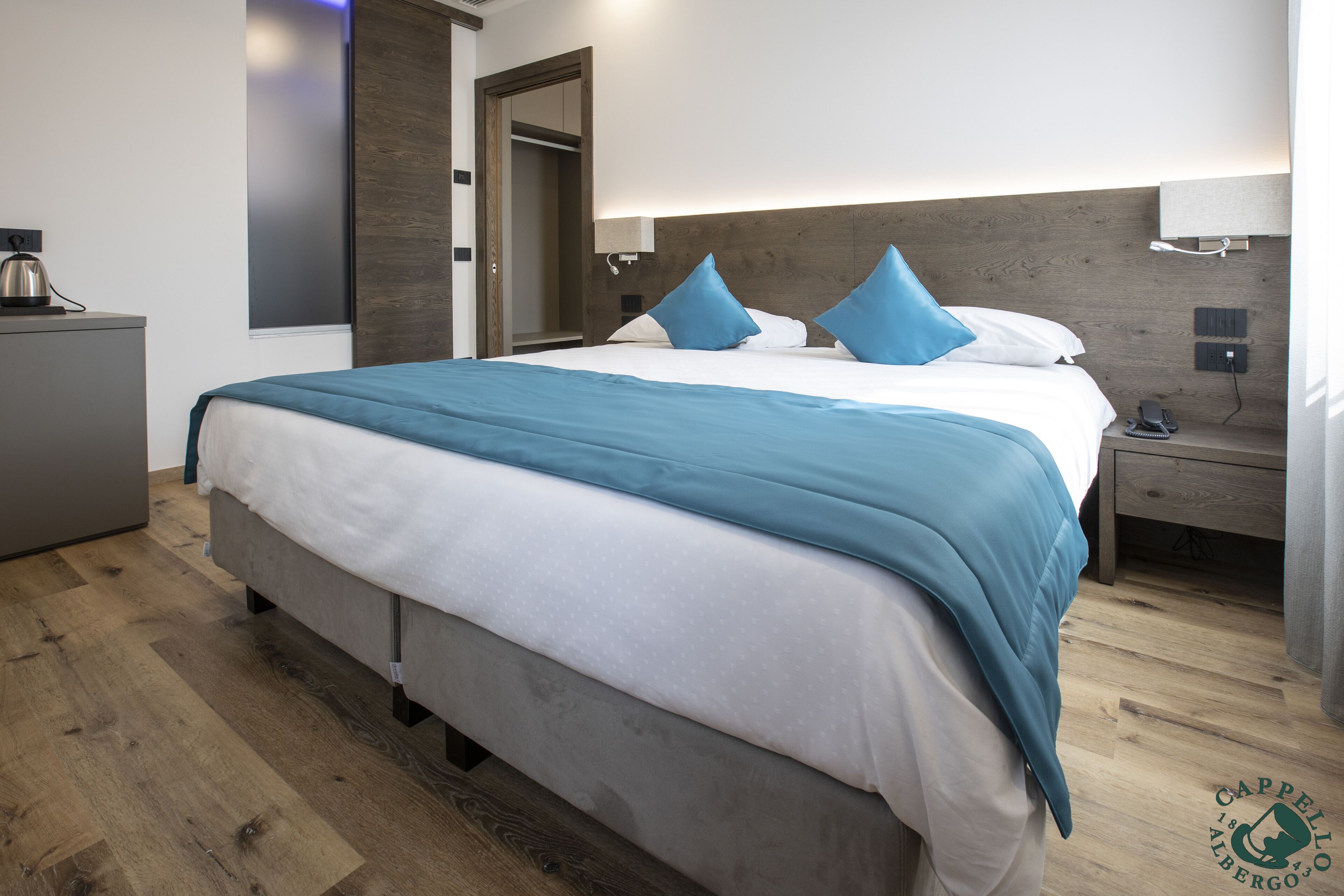 Quarto de hotel moderno com uma cama grande, uma mesa de cabeceira e um guarda-roupa.