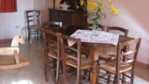 Uma sala de jantar com móveis de madeira, uma mesa com arranjo floral e um armário com espelho.