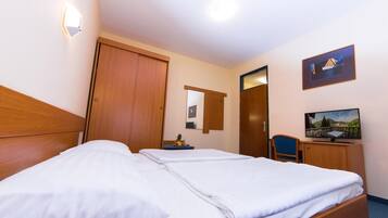 Quarto de hotel com duas camas, uma televisão, uma escrivaninha e um espelho.