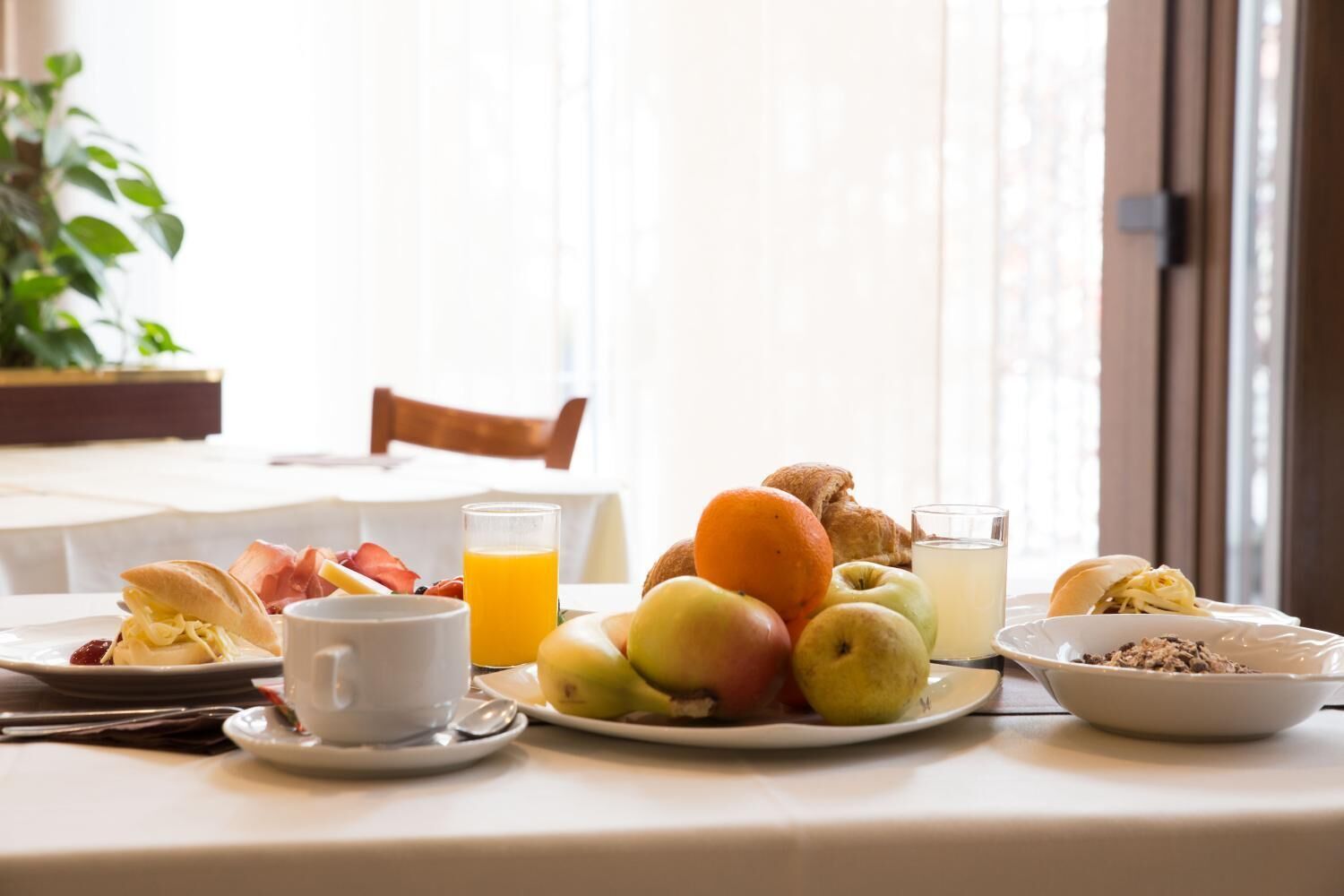 Uma mesa de café da manhã com pratos de comida, um copo de suco de laranja e um copo de leite.