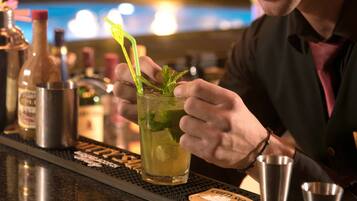 Um bartender preparando um cocktail com enfeite de limão e hortelã.
