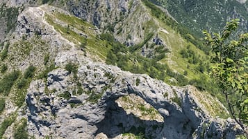 Paisagem montanhosa com terreno rochoso e vegetação verde densa.