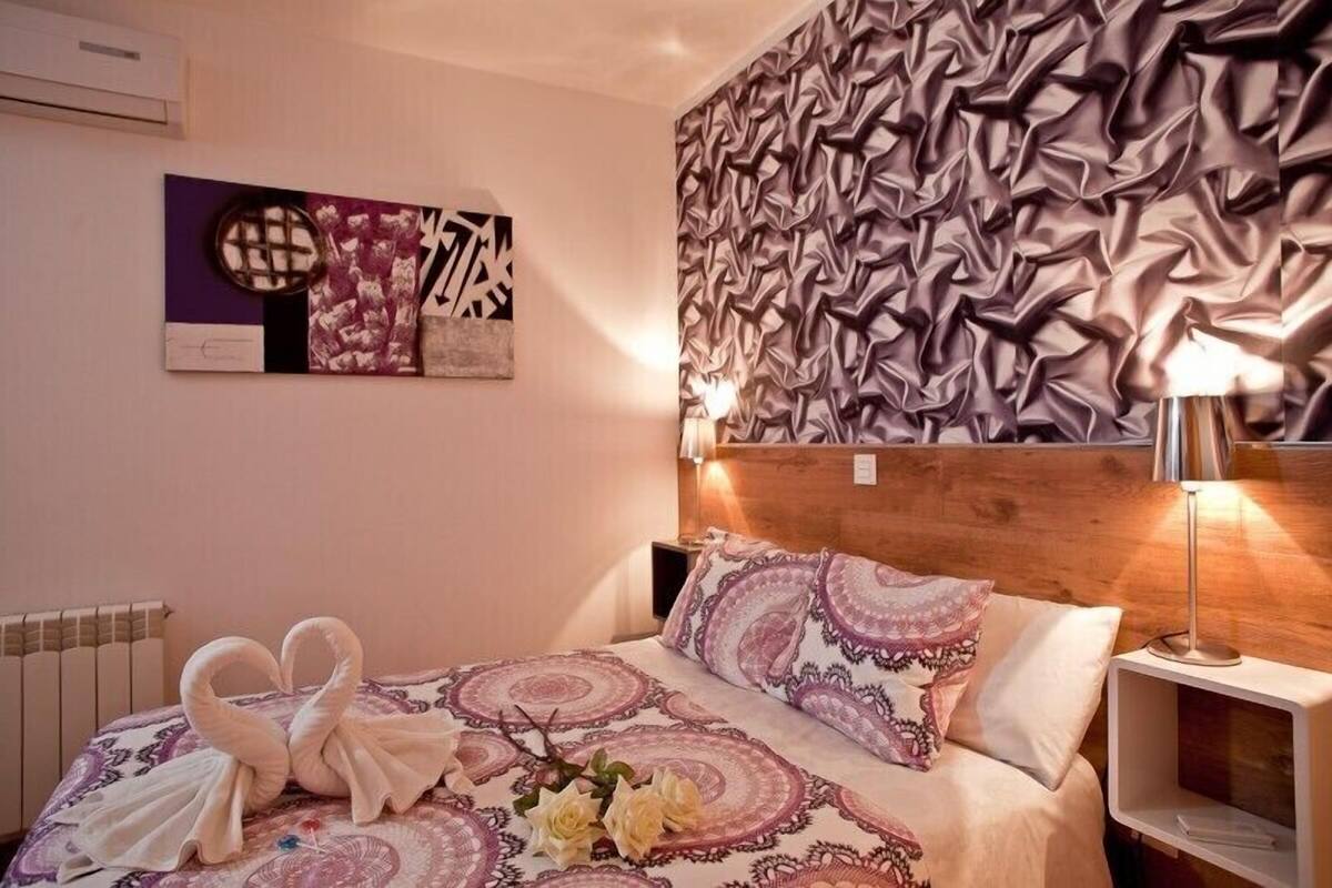 Quarto de hotel com cama, uma obra de arte na parede, parede estampada e abajur.