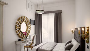 Quarto com uma cama grande, uma toucador com espelho, uma escrivaninha e um candelabro.