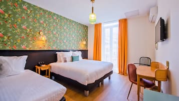 Quarto de hotel com duas camas, uma mesa de jantar e uma televisão.