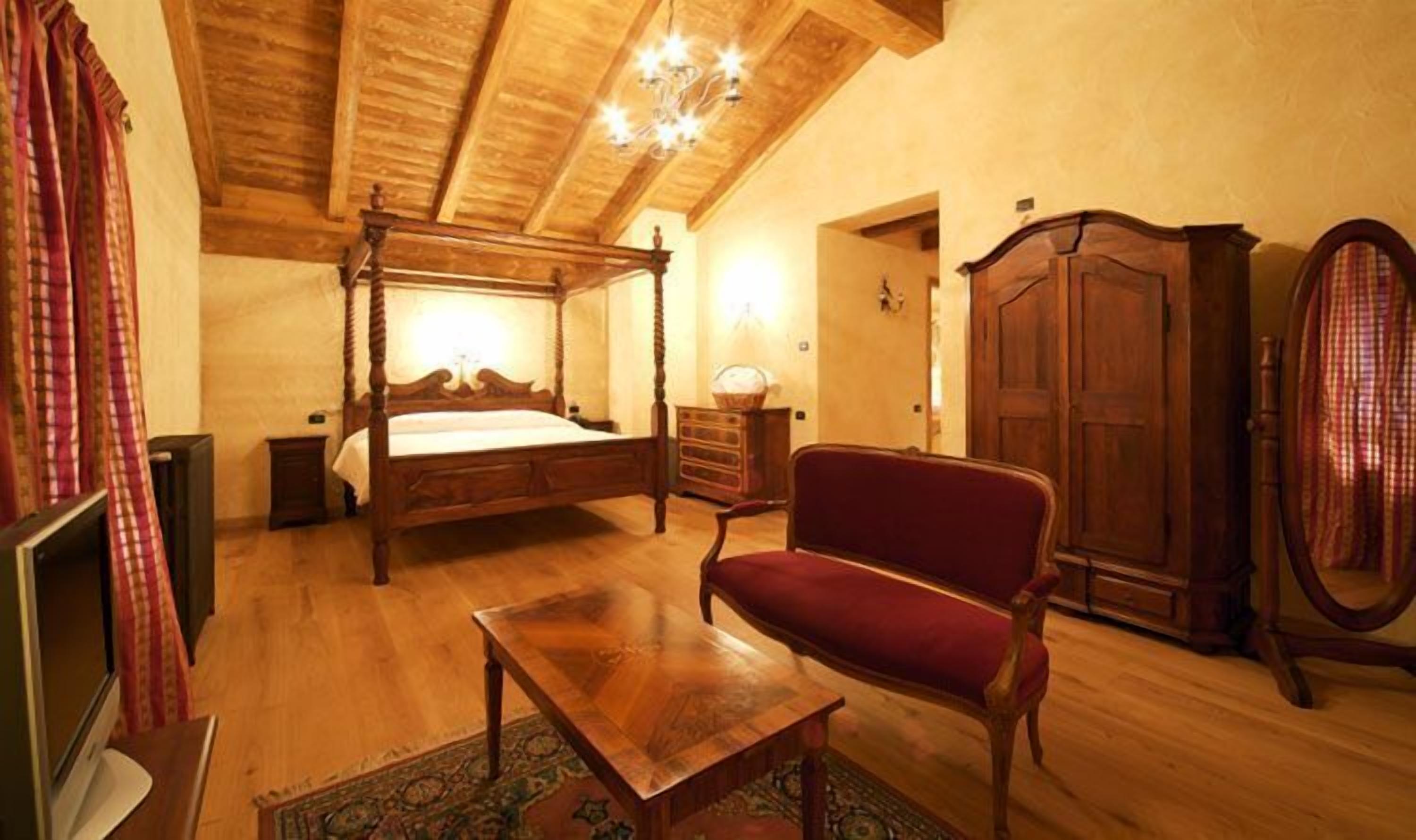 Um quarto tradicional com uma cama de dossel, um guarda-roupa de madeira, uma poltrona estofada vermelha e uma mesa de madeira.